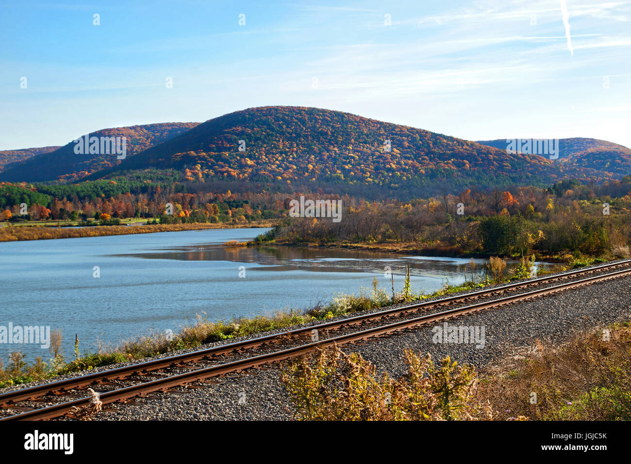 Rail road track running along a peaceful lake with fall colors in the ...