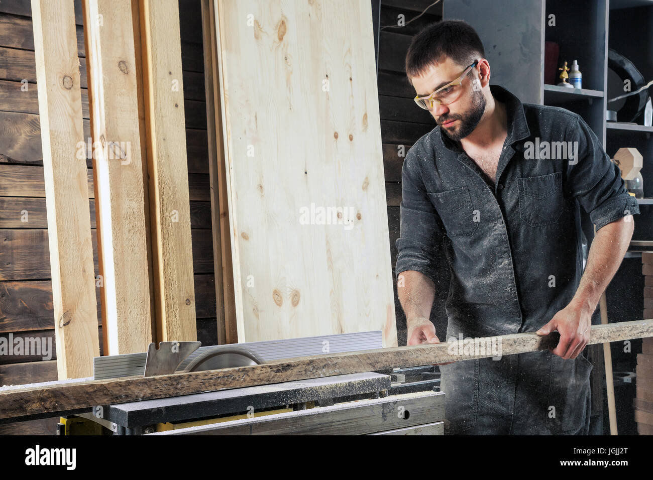 Young male construction worker carpenter sawing a circular saw blade in ...