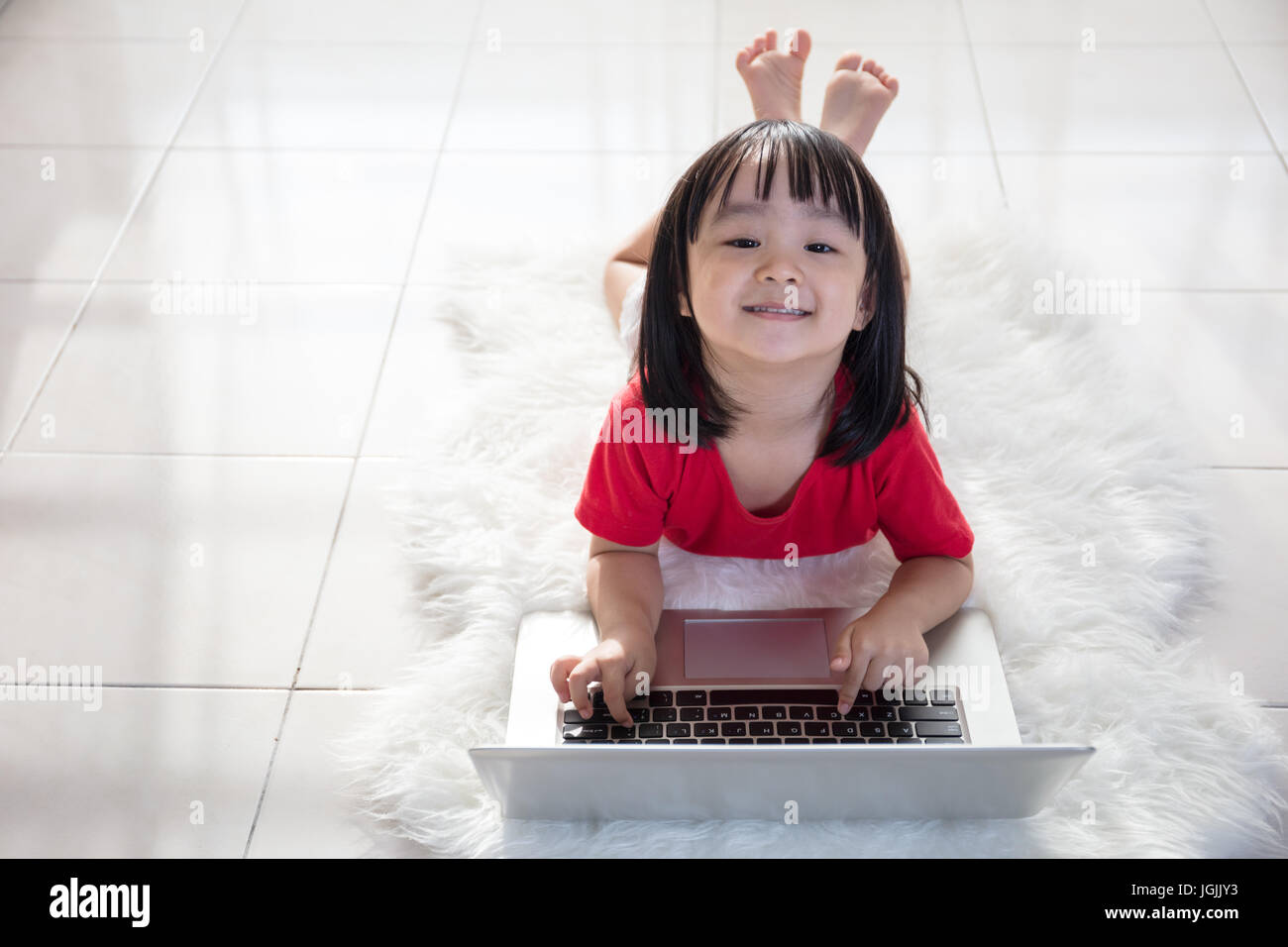Asian Chinese little girl with laptop lying on the floor at home Stock ...