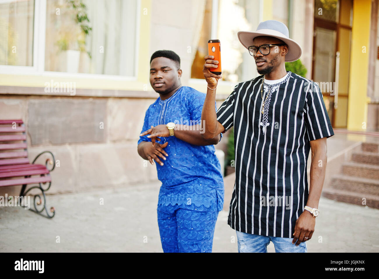 Black men stylishly clothed standing and talking outside on the street ...