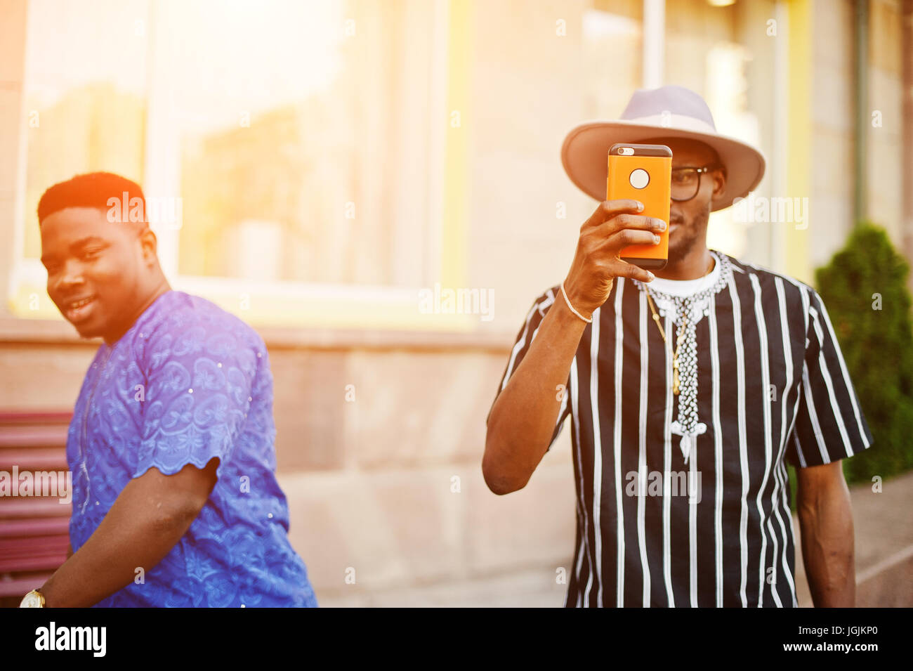 Black men stylishly clothed standing and talking outside on the street ...