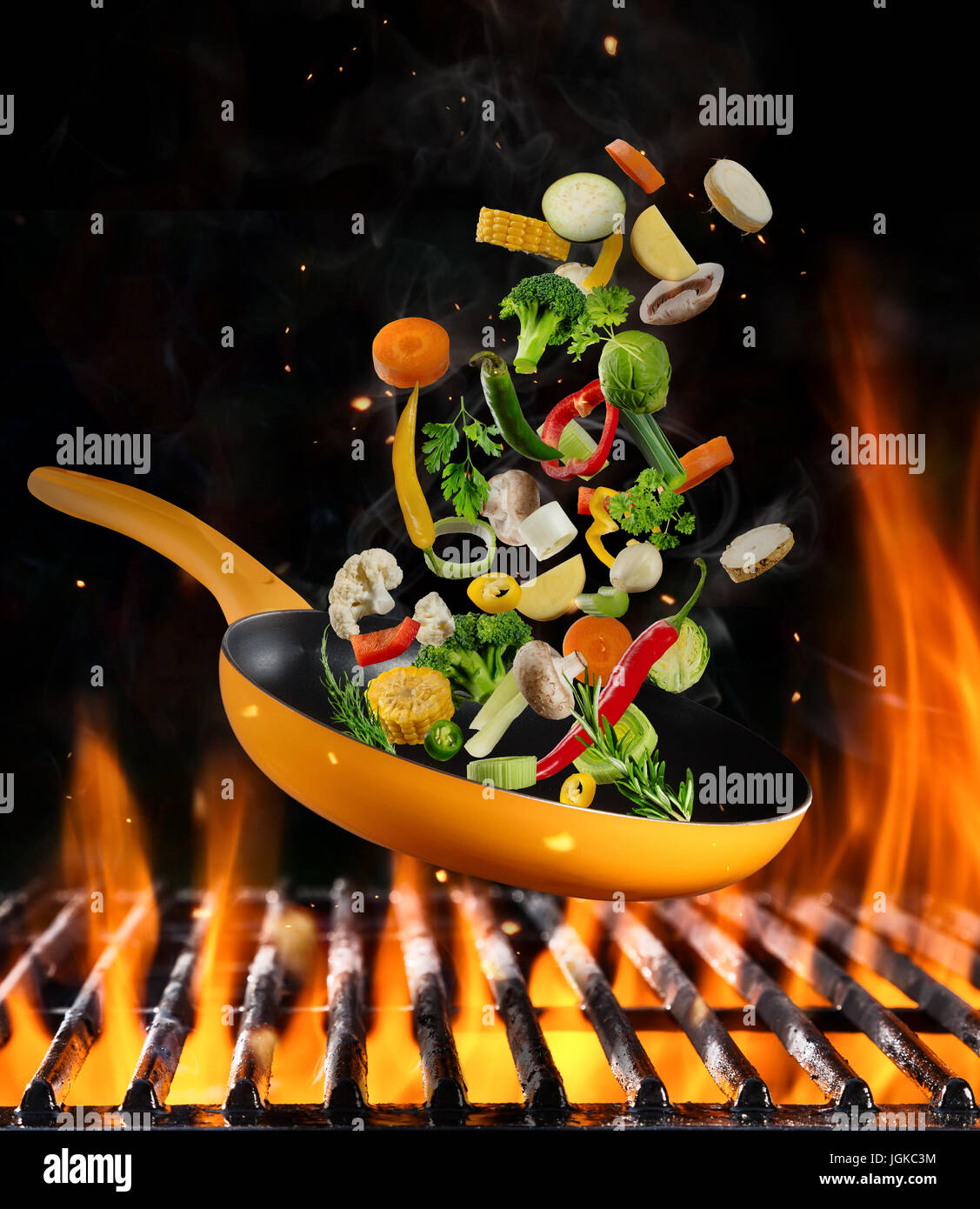 Fresh vegetable flying above grill with flames on black background ...