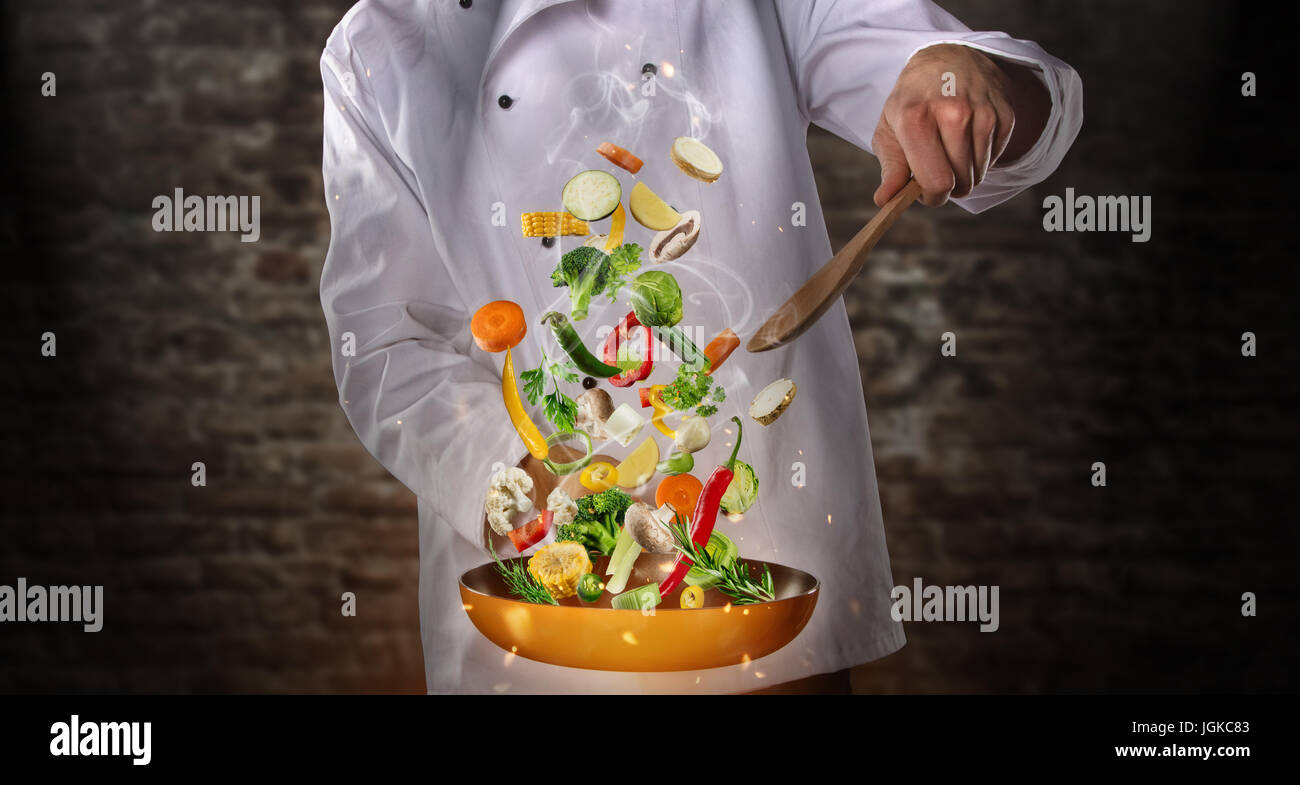 Closeup of chef cooker preparing vegetable on fire, flying motion ...