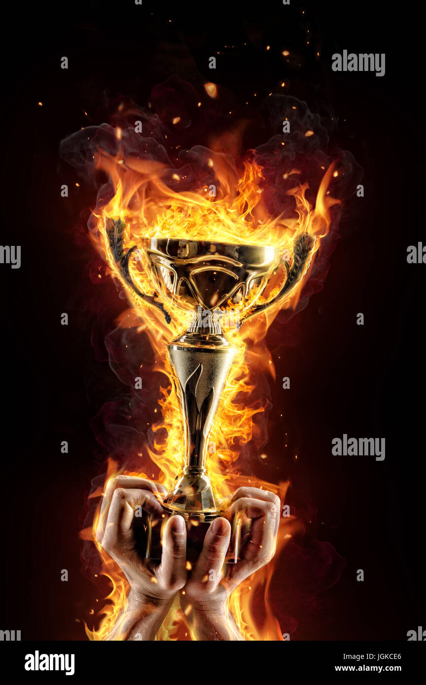 Man hands holding burning gold trophy cup as a winner, flames around ...
