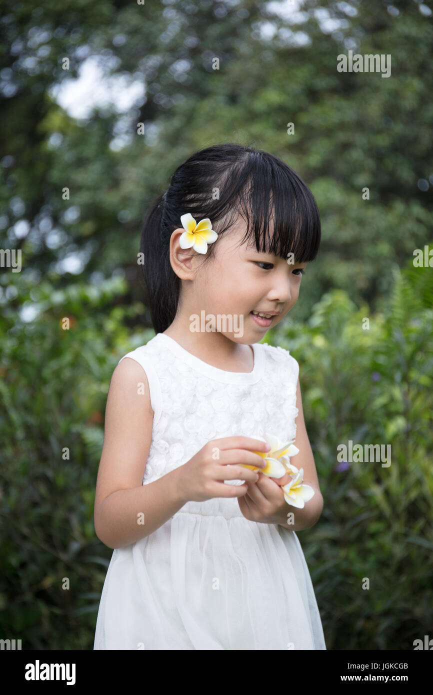 Asian Chinese little girl holding flowers in outdoor garden on day time ...
