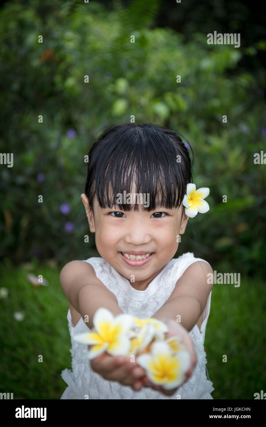 Asian Chinese little girl holding flowers in outdoor garden on day time ...