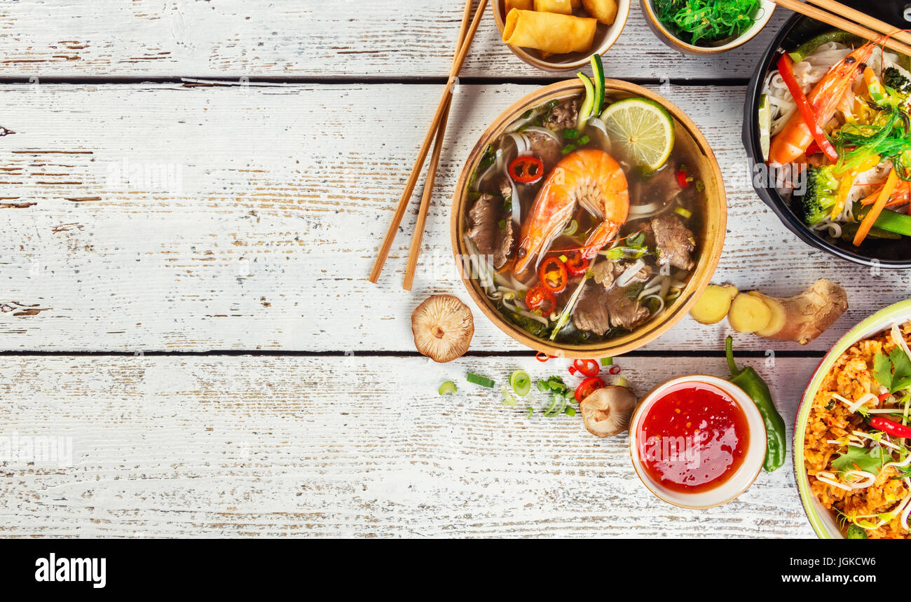 Asian food served on white wooden table, top view, space for text ...