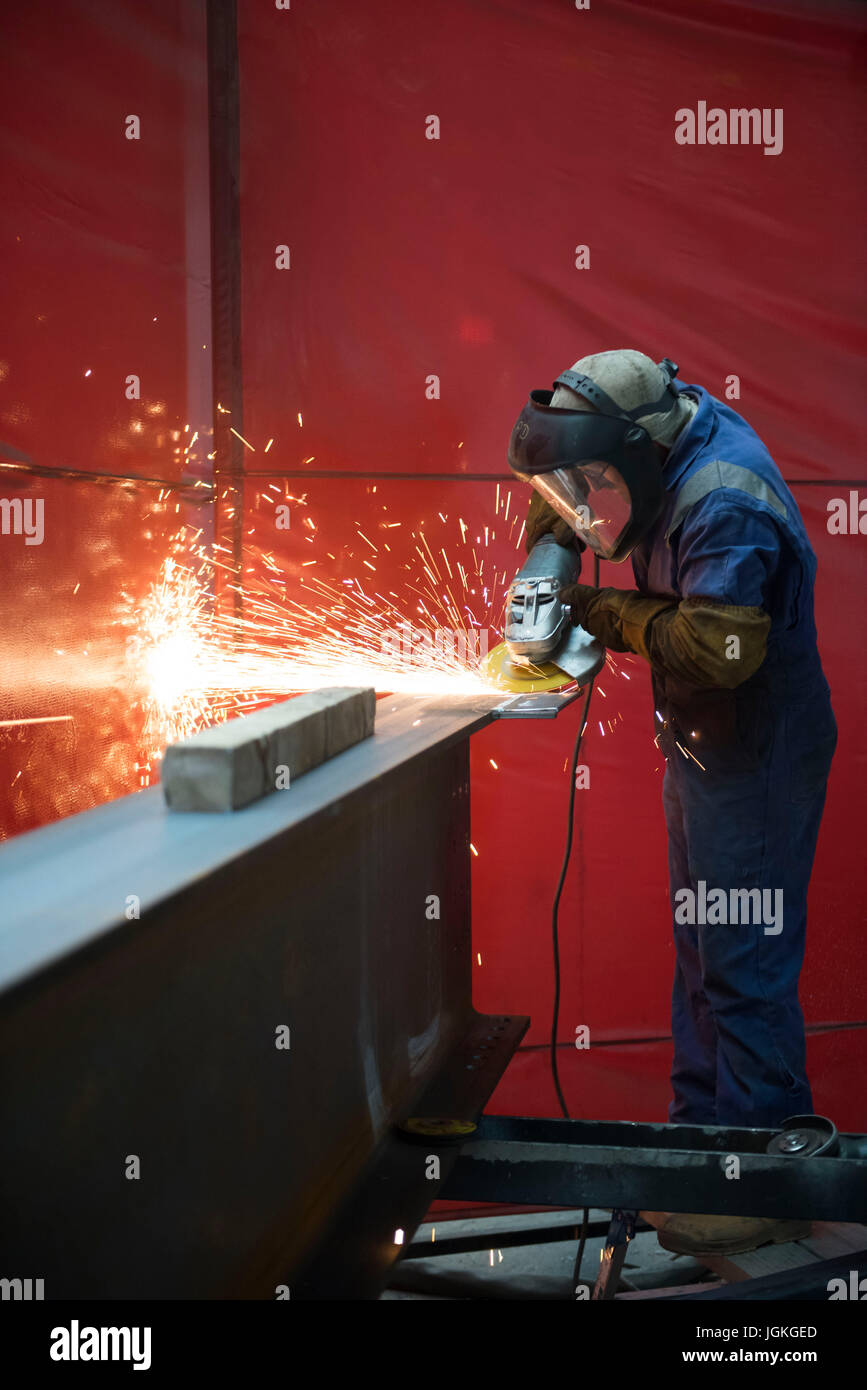 Workers at a steel fabrication facility welding and grinding steel in ...