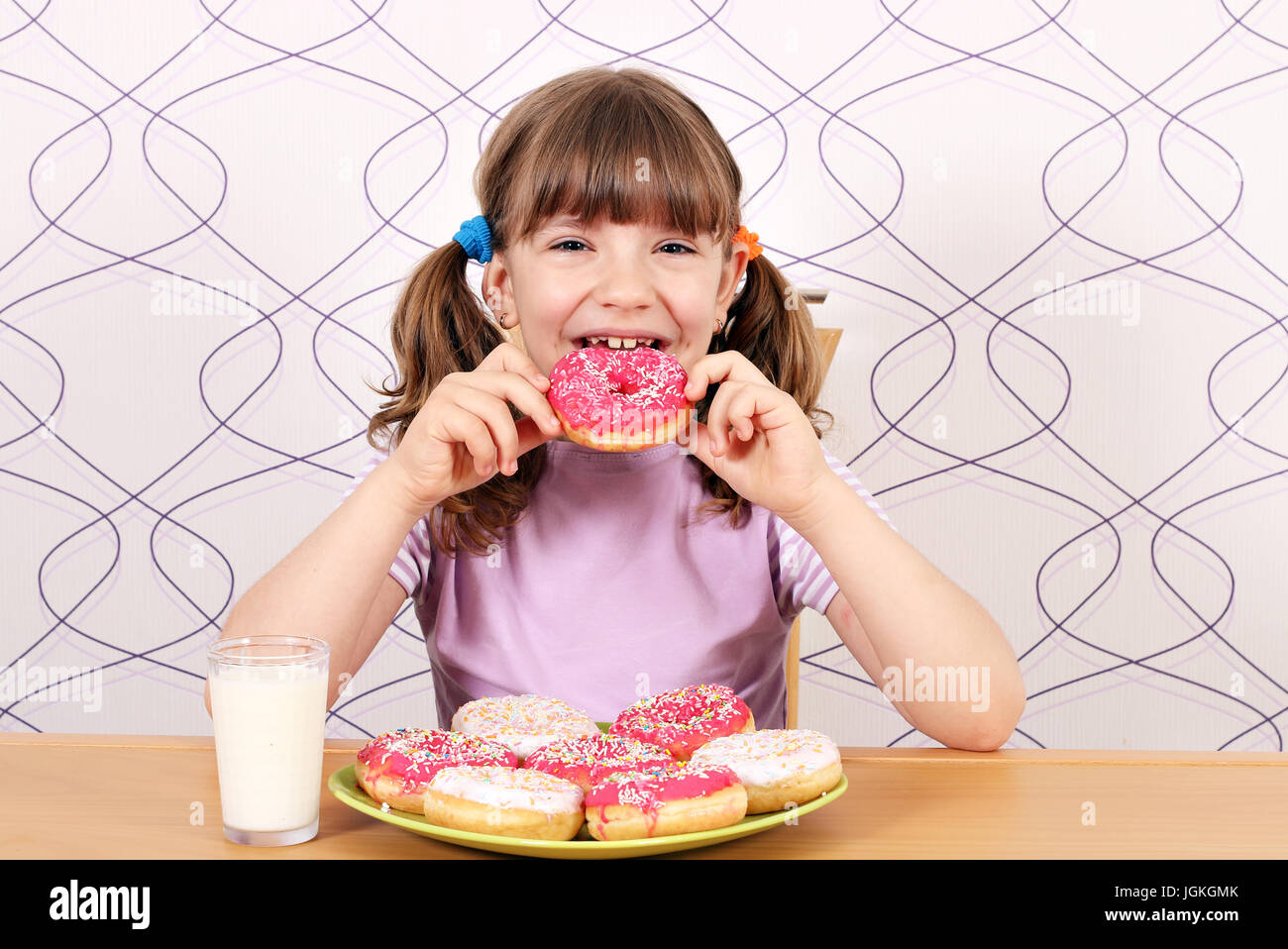 hungry little girl eating donuts Stock Photo - Alamy