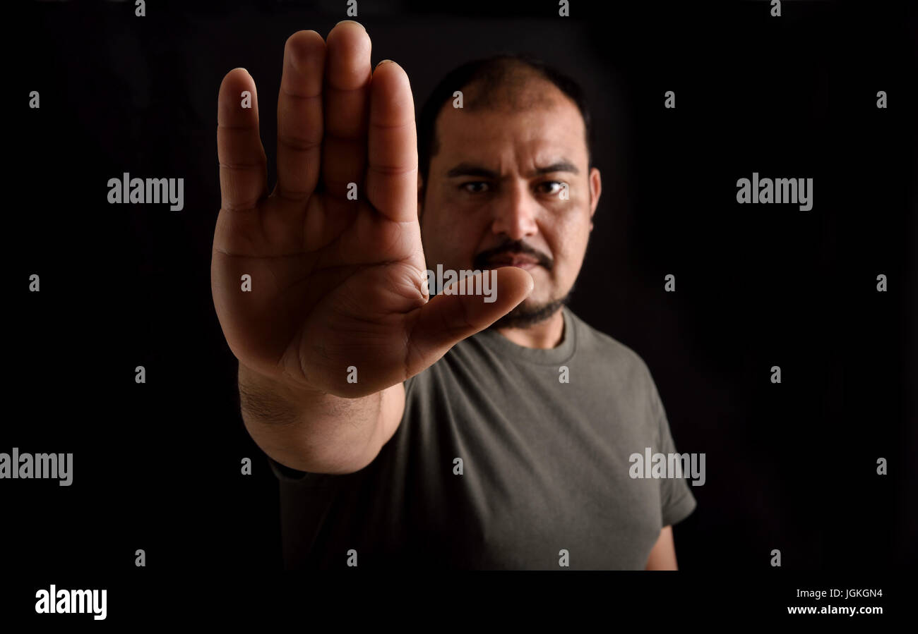 Portrait of a latin man with stop sing on black Stock Photo - Alamy