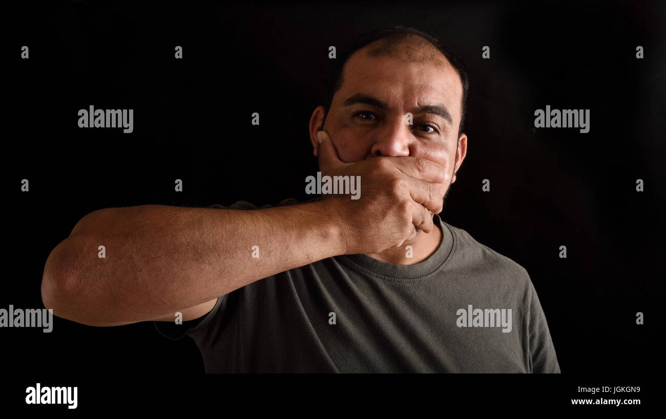 Man covering his mouth on black background Stock Photo - Alamy