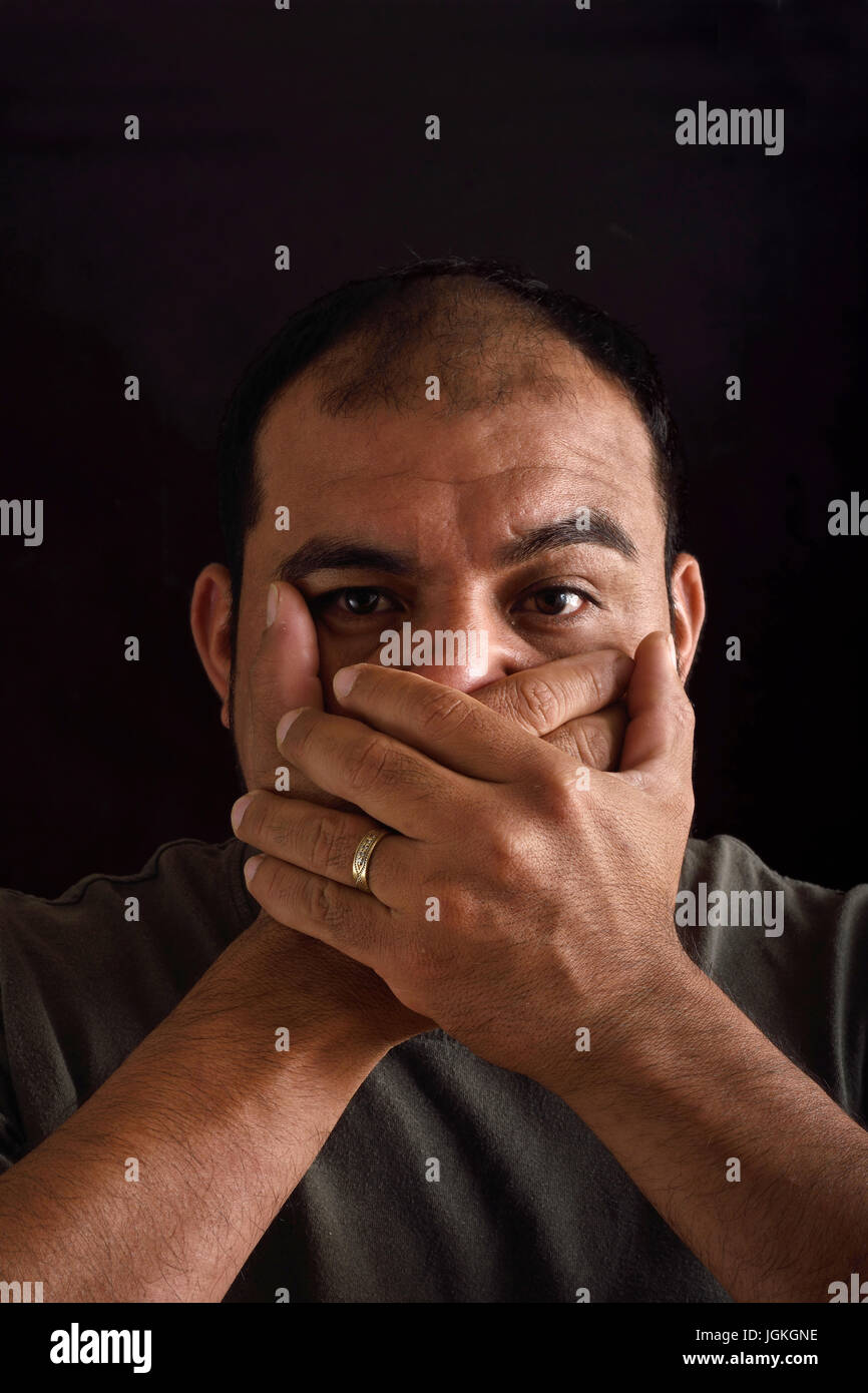 Man covering his mouth on black background Stock Photo - Alamy