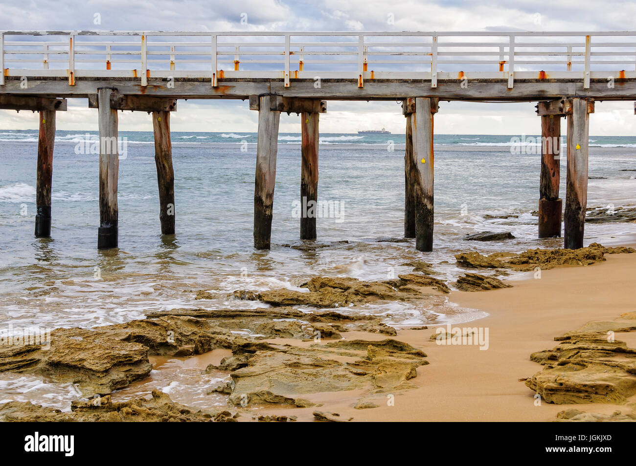 Old pillars of the Point Lonsdale Pier with a container ship on the ...