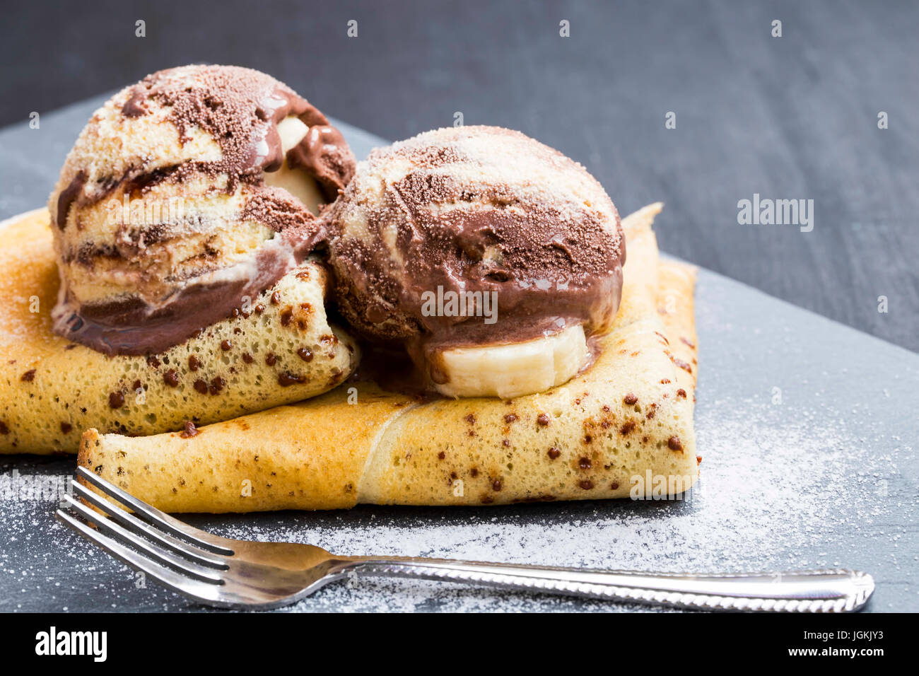 Delicious crepes filled with chocolate sauce, with ice cream scoops on ...