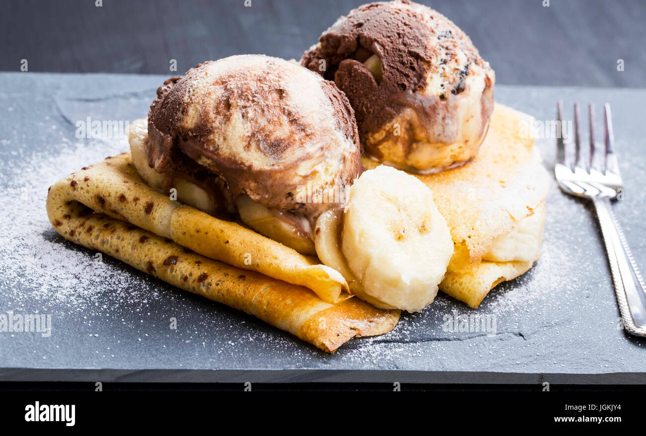 Delicious crepes filled with chocolate sauce, with ice cream scoops on ...