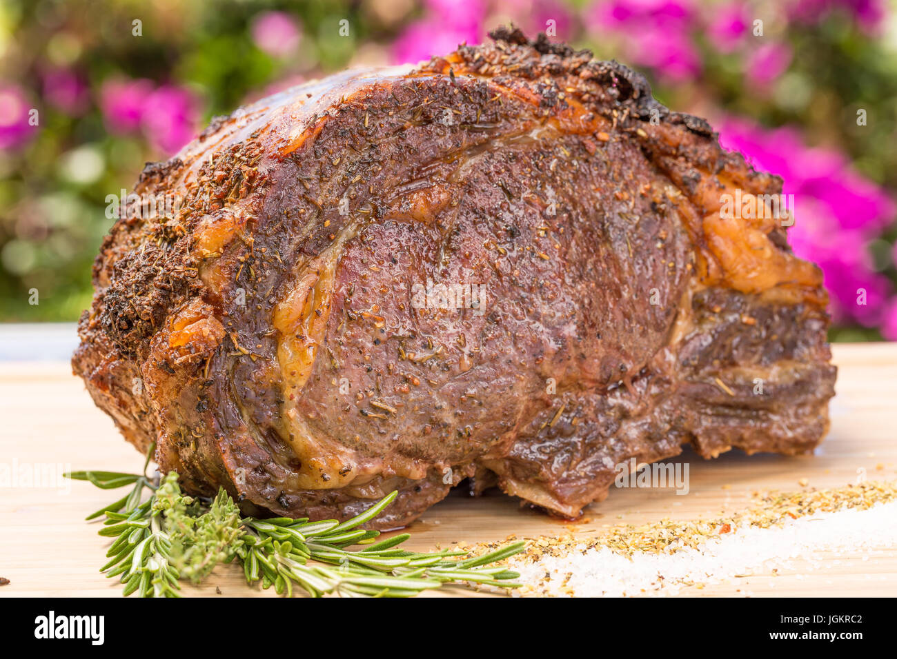 A large prime rib cut of beef roasted on a cutting board with salt and ...