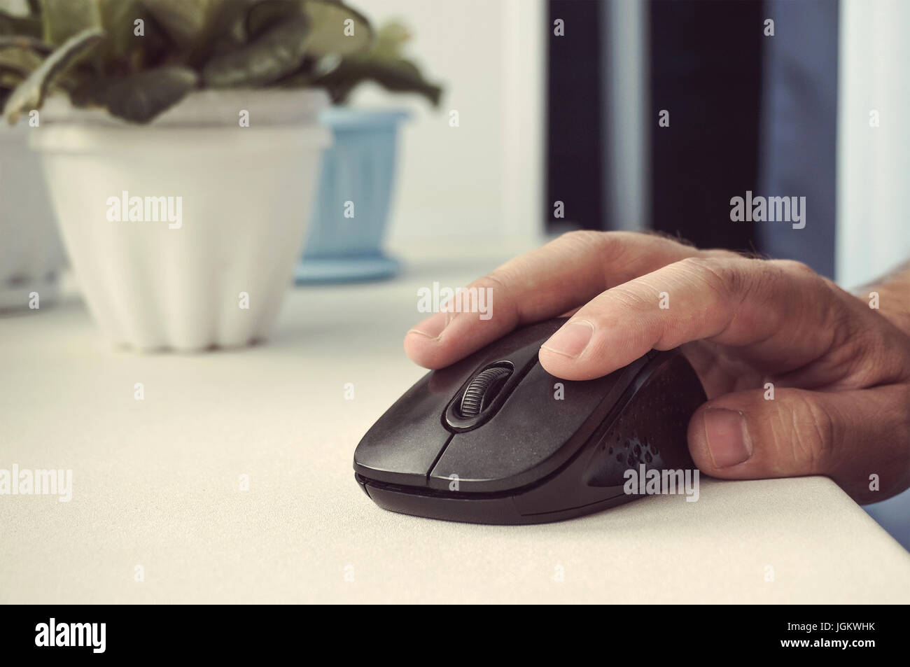 Black computer mouse in the hand of man on the white Desk. Working in ...