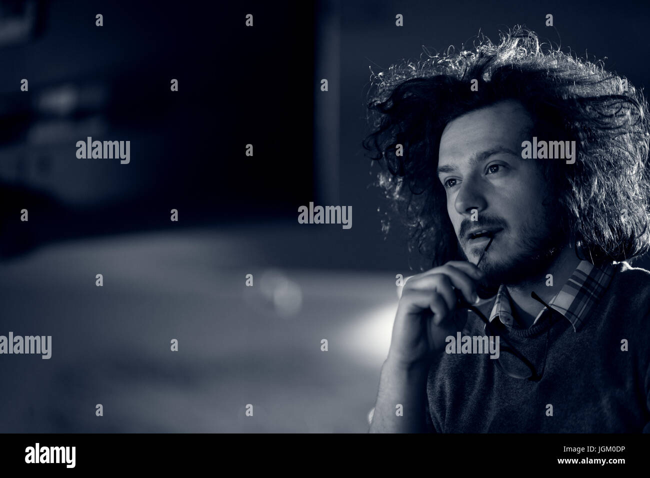 Young man working on computer at night in dark office. The designer ...