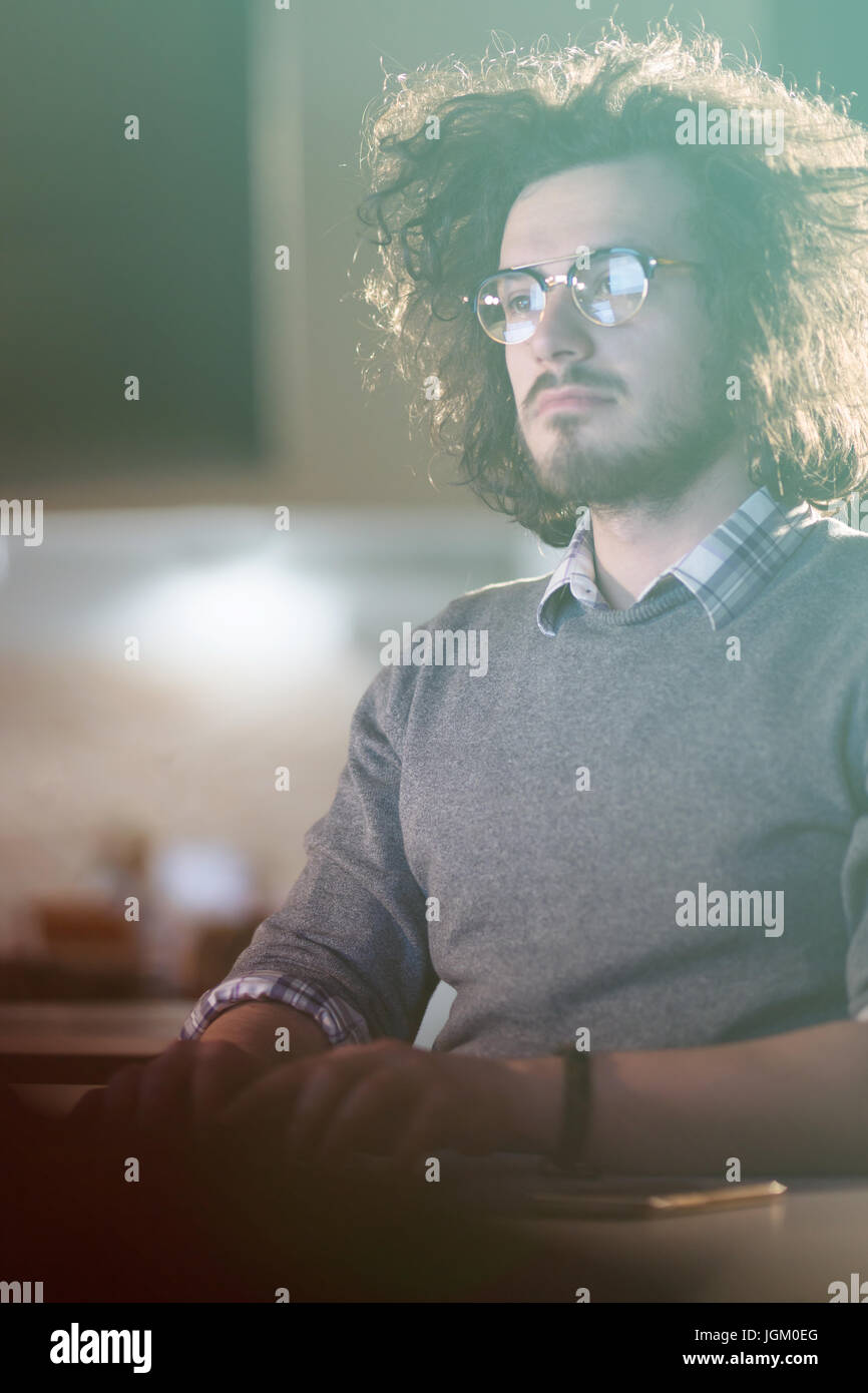 Young man working on computer at night in dark office. The designer ...