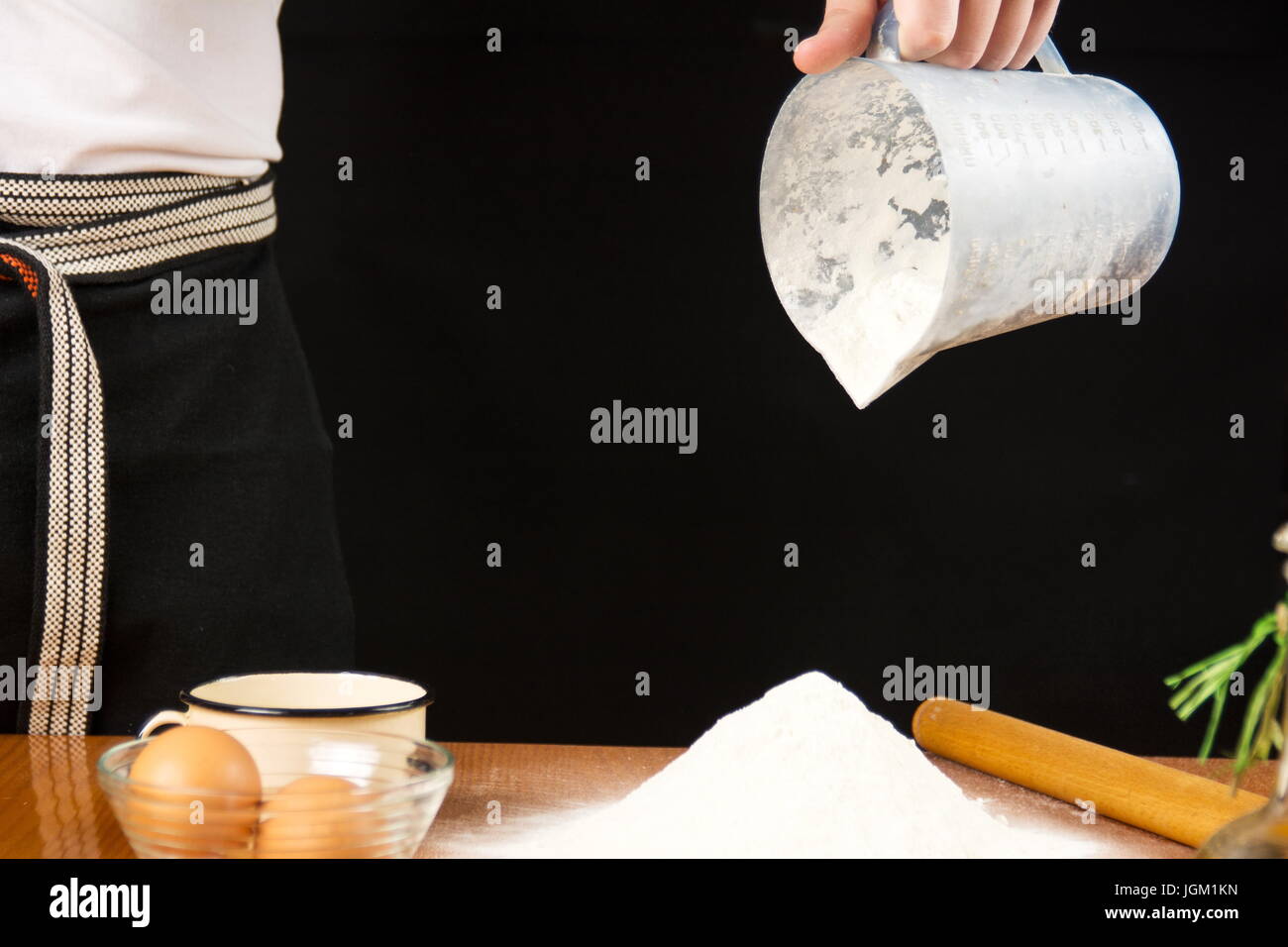 Man pouring flour from the measure bowl on the table Stock Photo - Alamy