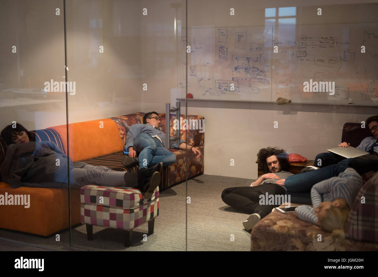 group of young casual software developer sleeping on sofa during a work ...