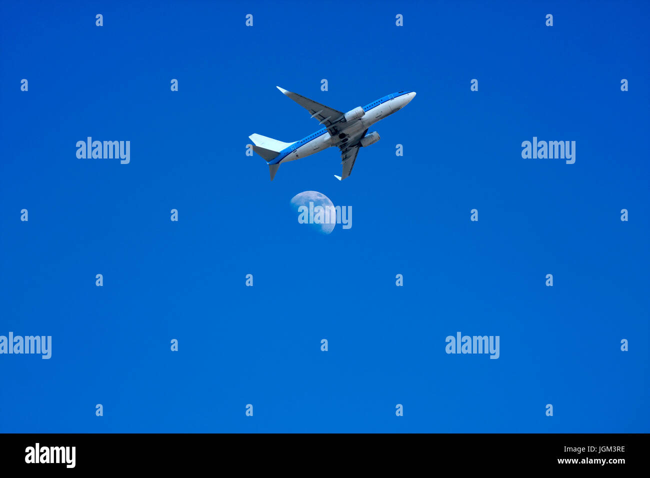 Jet plane flying over the moon in a blue sky Stock Photo - Alamy