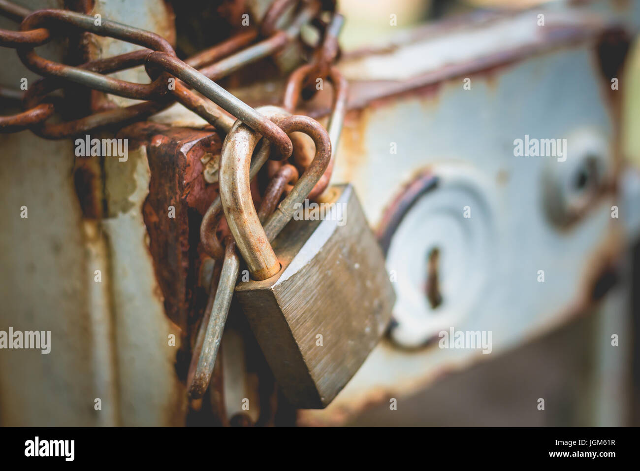 Old lock closing a rusty chain surrounding a wrought iron door Stock ...