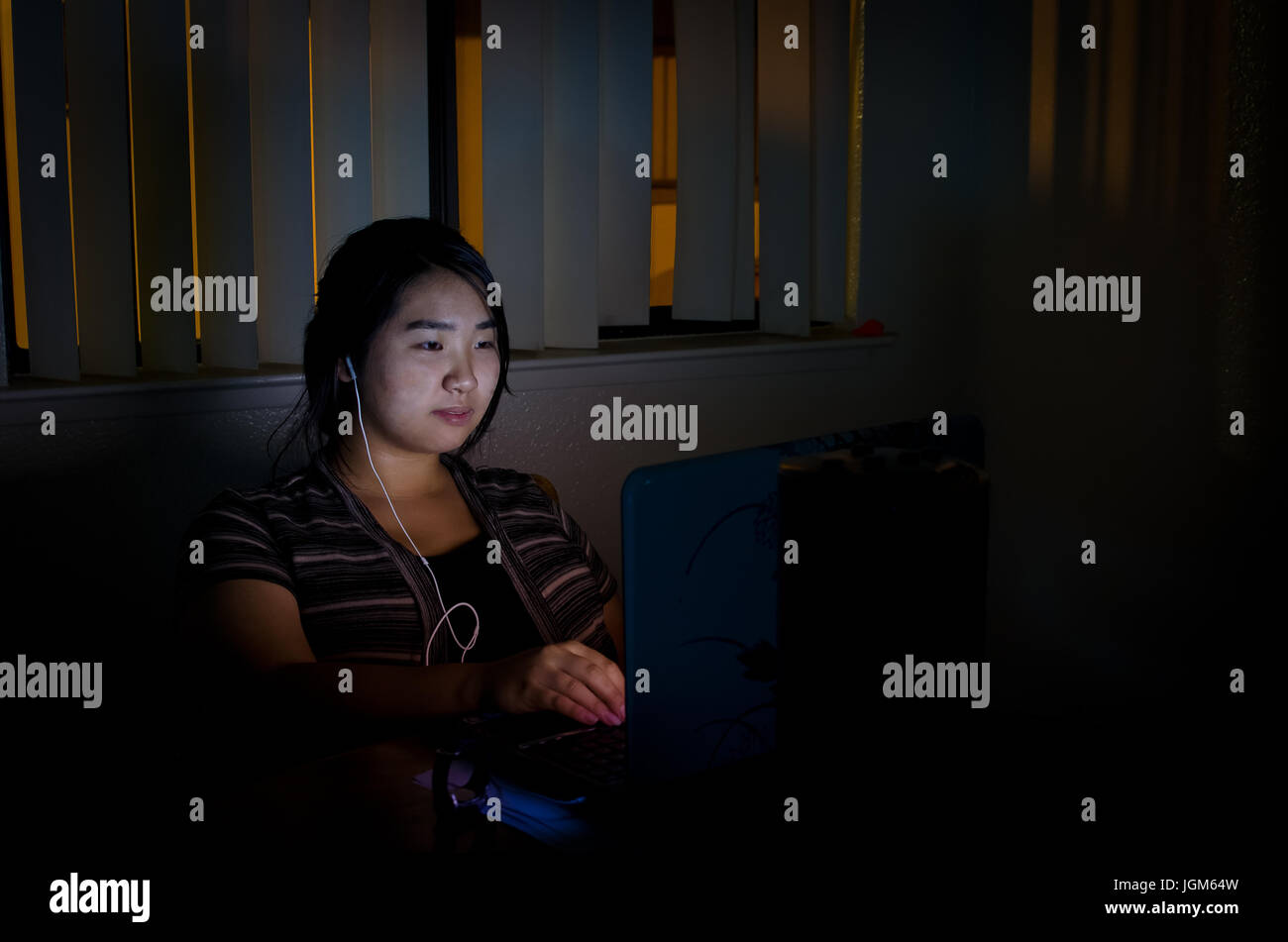Girl sitting in the dark working on her laptop Stock Photo - Alamy