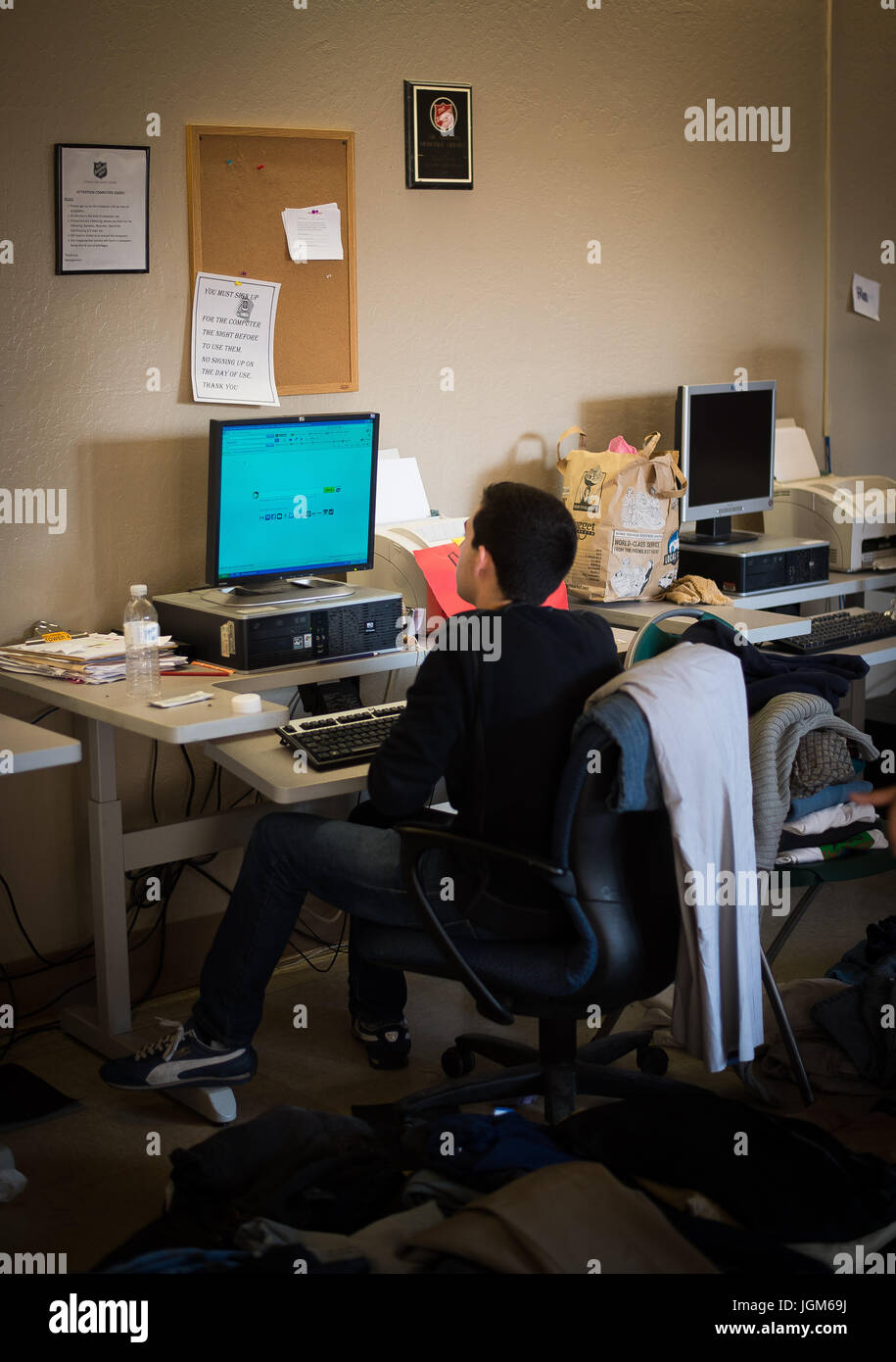 Man sitting at a computer working Stock Photo - Alamy
