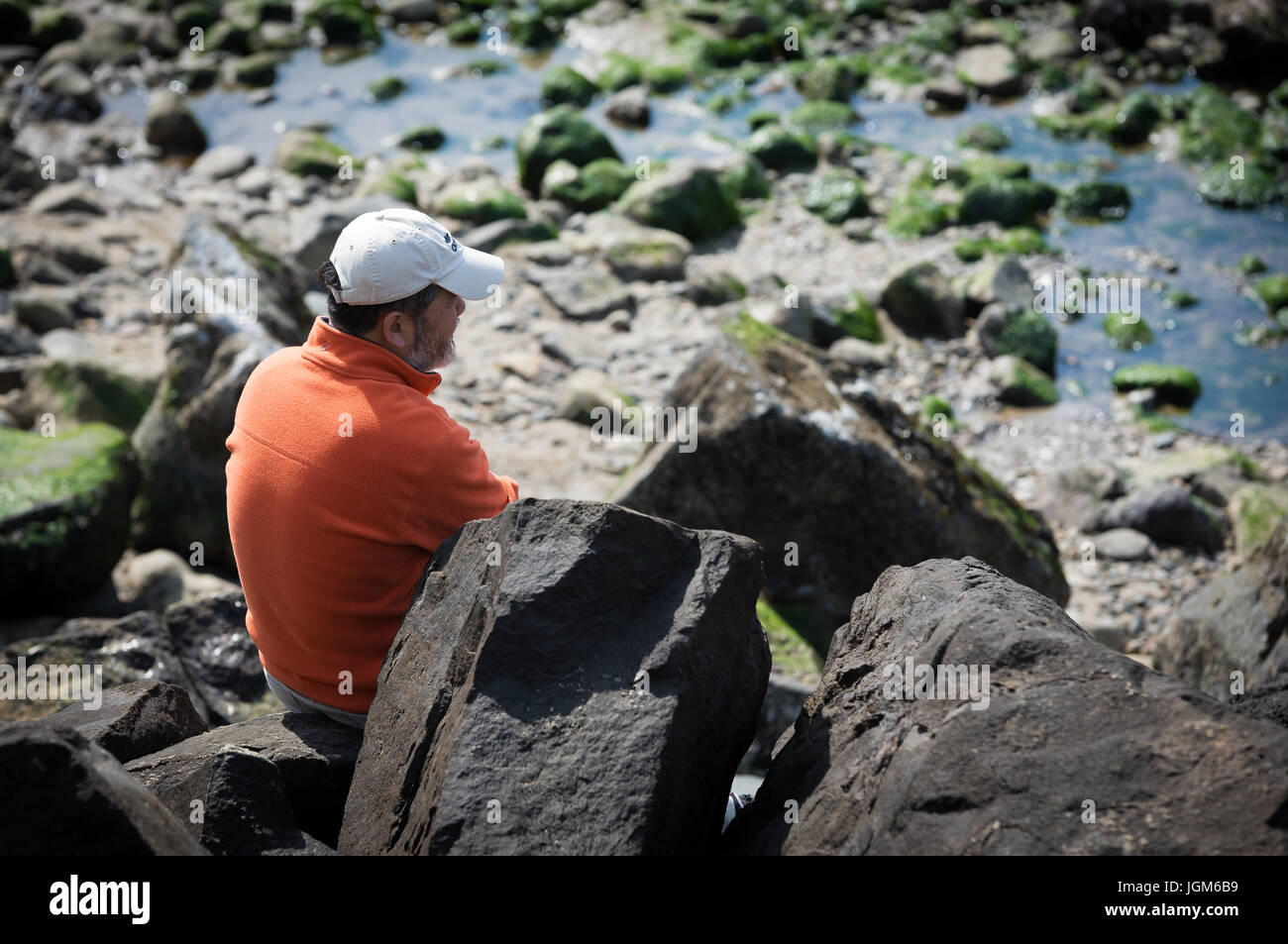 Man sitting on rocks resting Stock Photo - Alamy