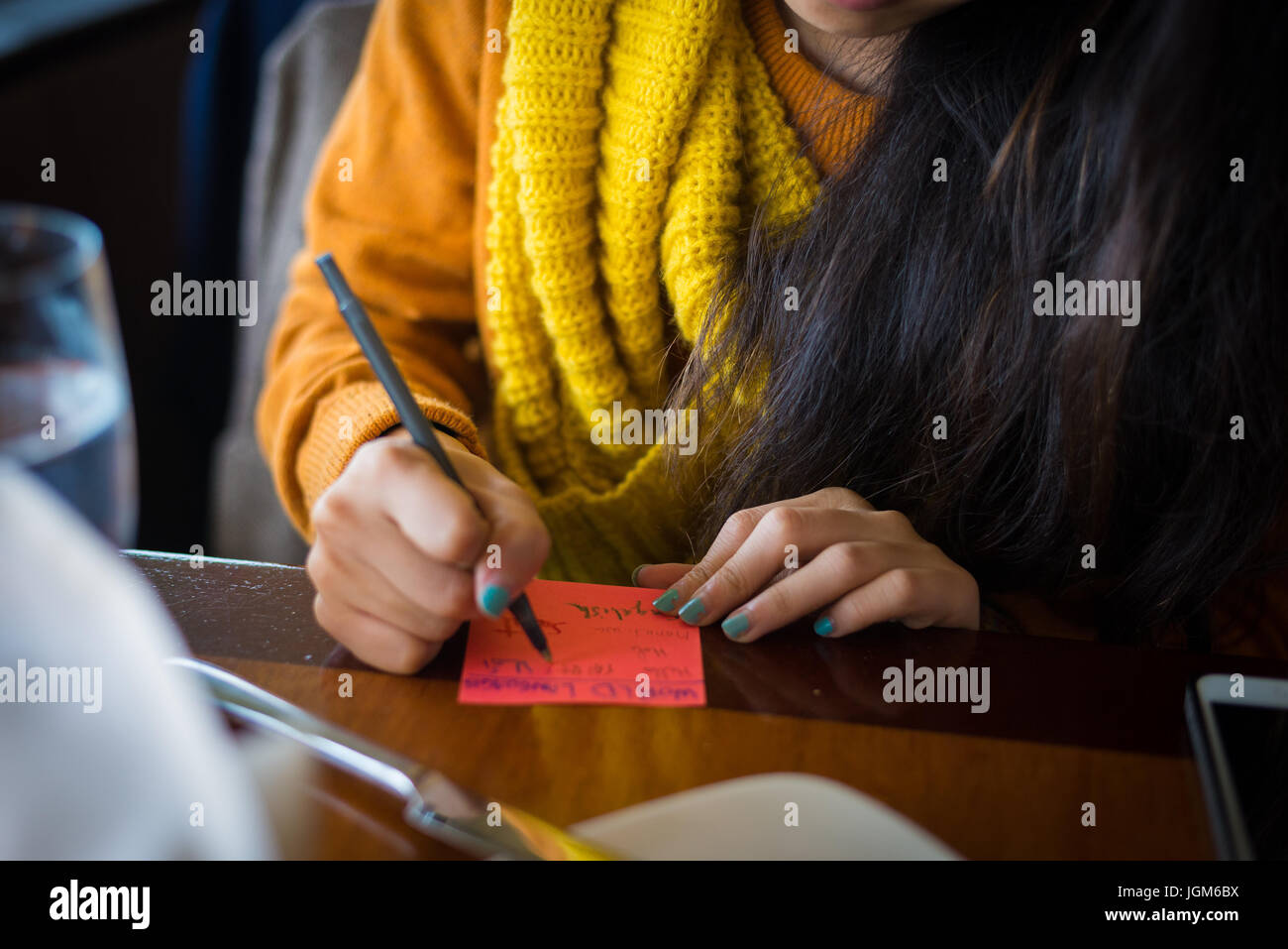 Girl with painted nails writing on a post-it note Stock Photo - Alamy