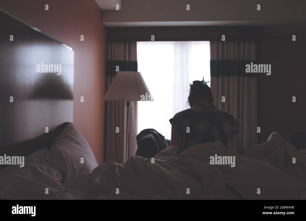 Girl sitting on hotel bed with her back facing camera Stock Photo - Alamy