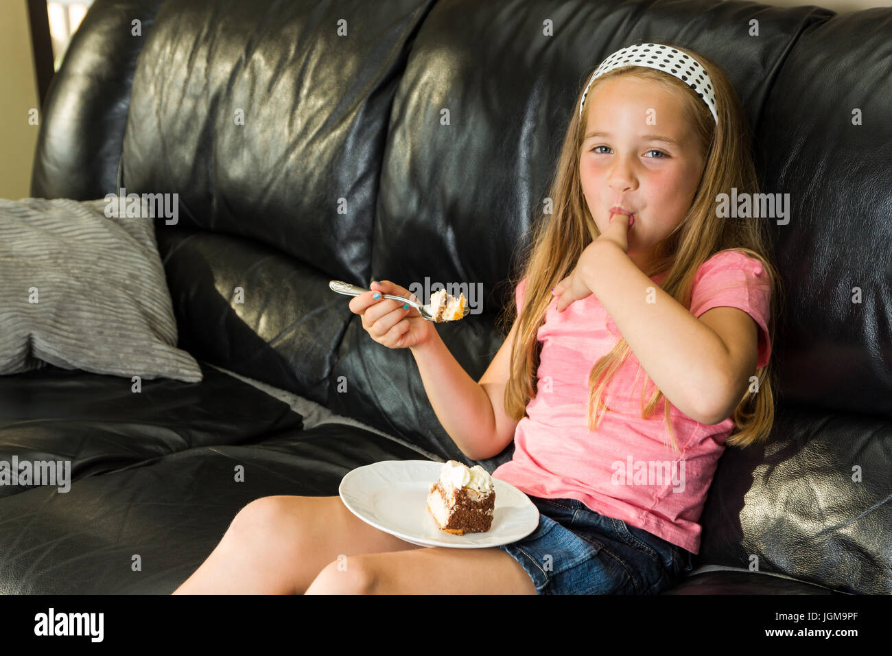 Pretty young girl enjoys eating dessert on the couch Stock Photo - Alamy