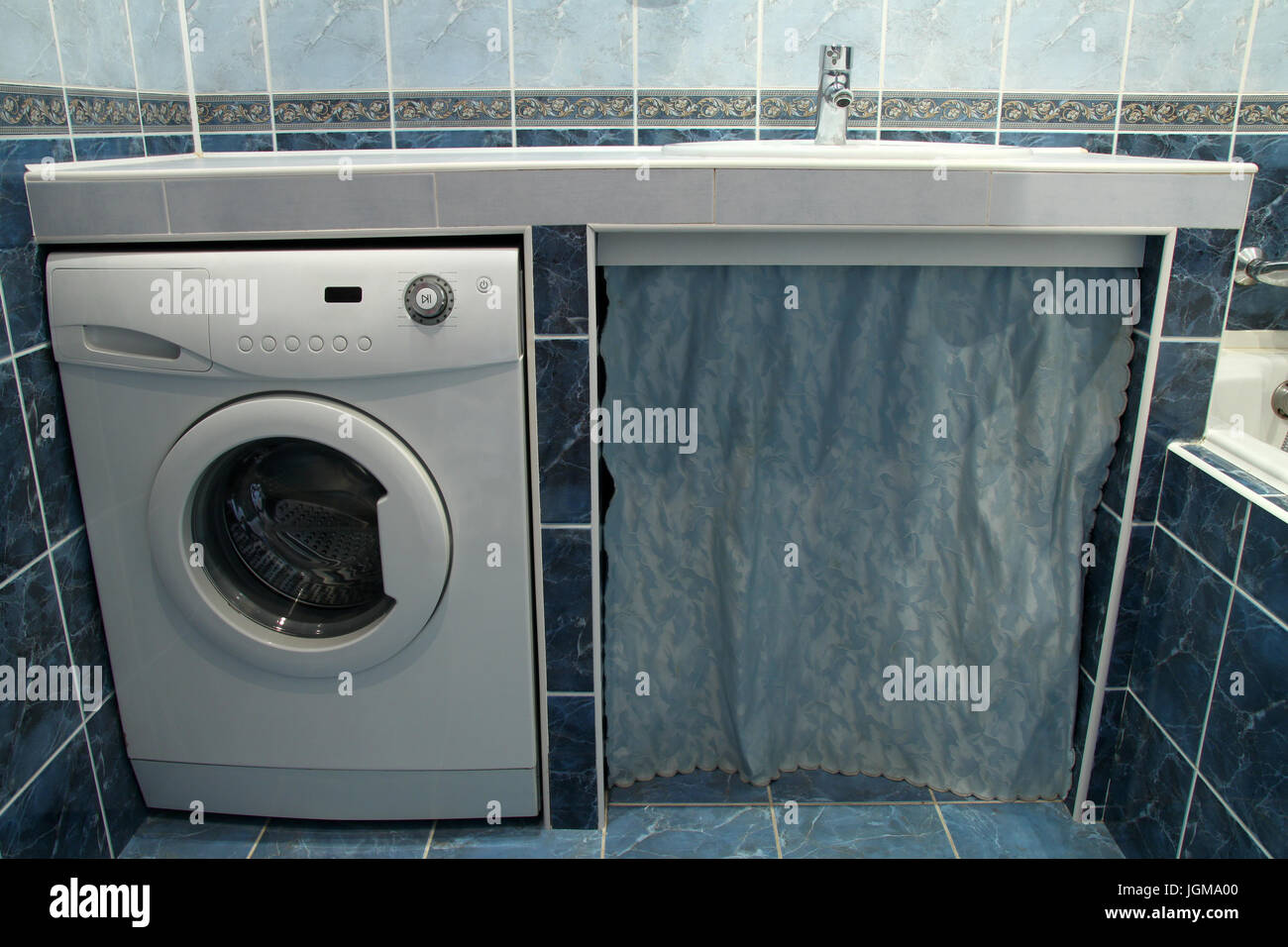 Modern bathroom with blue tiles and washing machine Stock Photo - Alamy