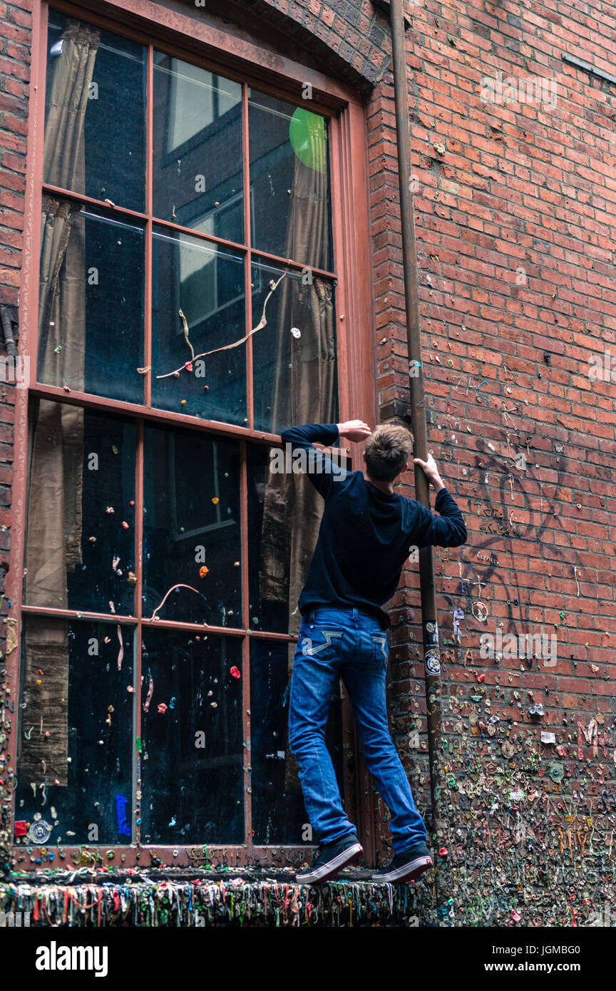 Boy climbing a window ledge in Seattle's gum wall Stock Photo - Alamy