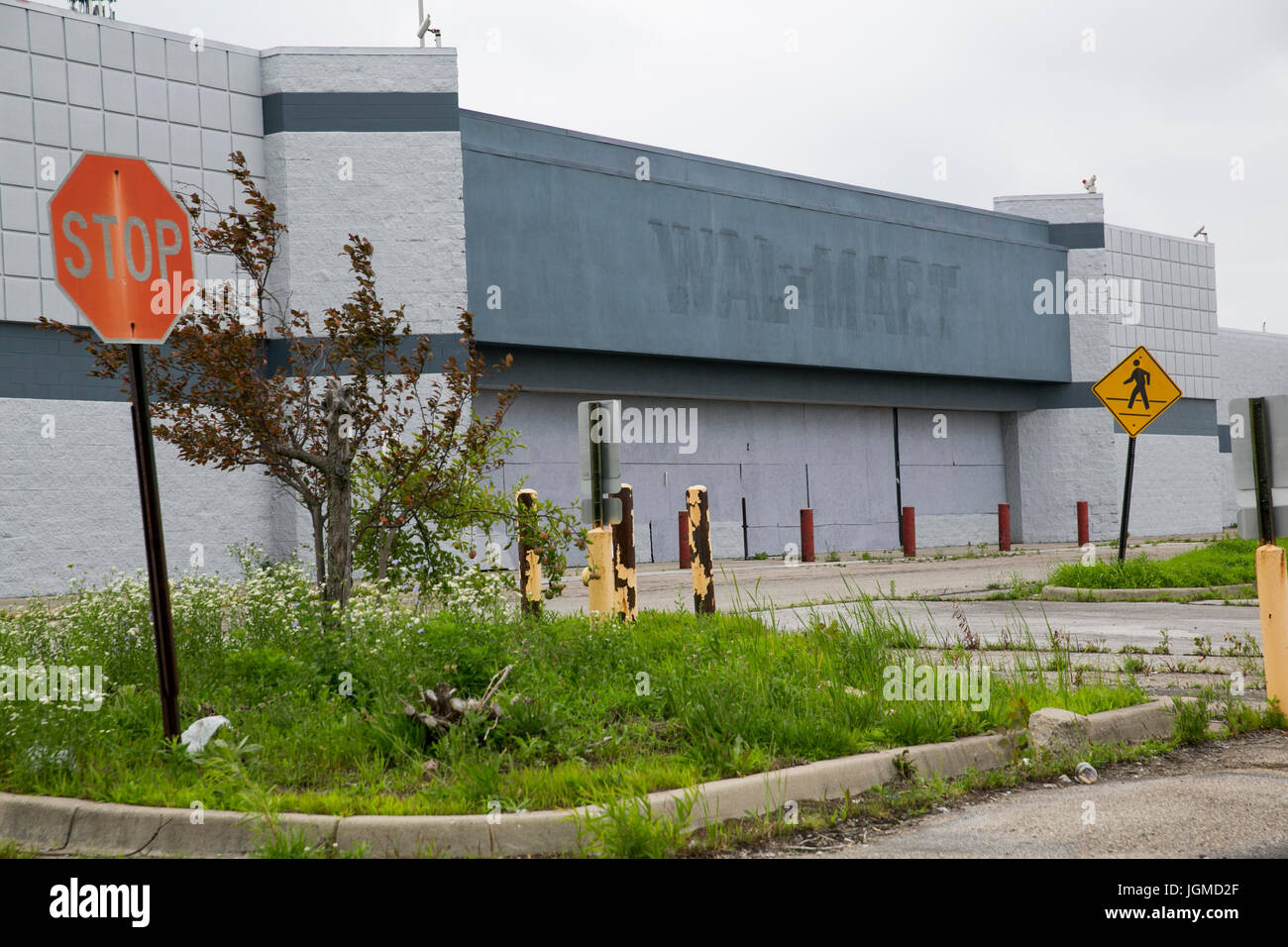 A logo sign outside of a closed and abandoned Walmart retail store in ...