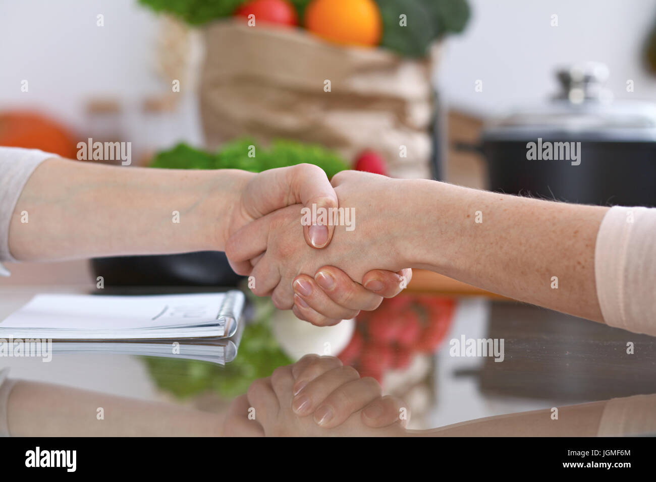 Close-up of shaking hands over a table in the kitchen. Friends having ...