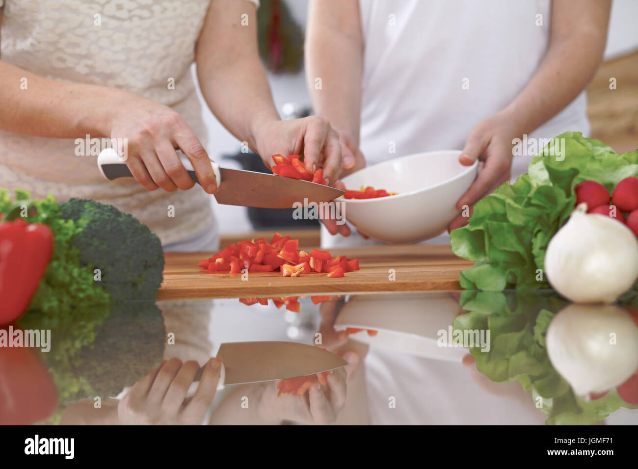 Close-up of four human hands are cooking in a kitchen. Friends having ...