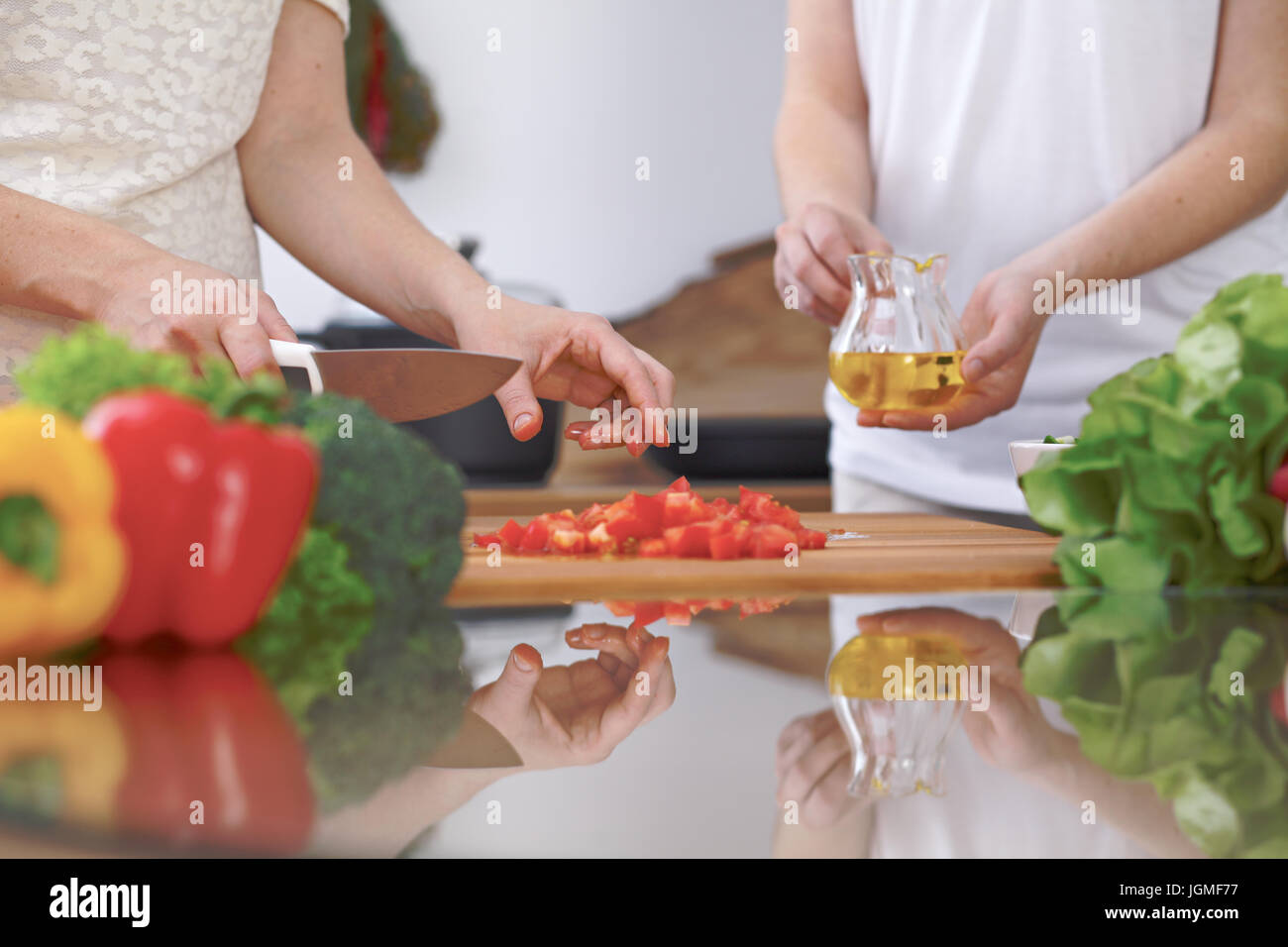 Close-up of four human hands are cooking in a kitchen. Friends having ...