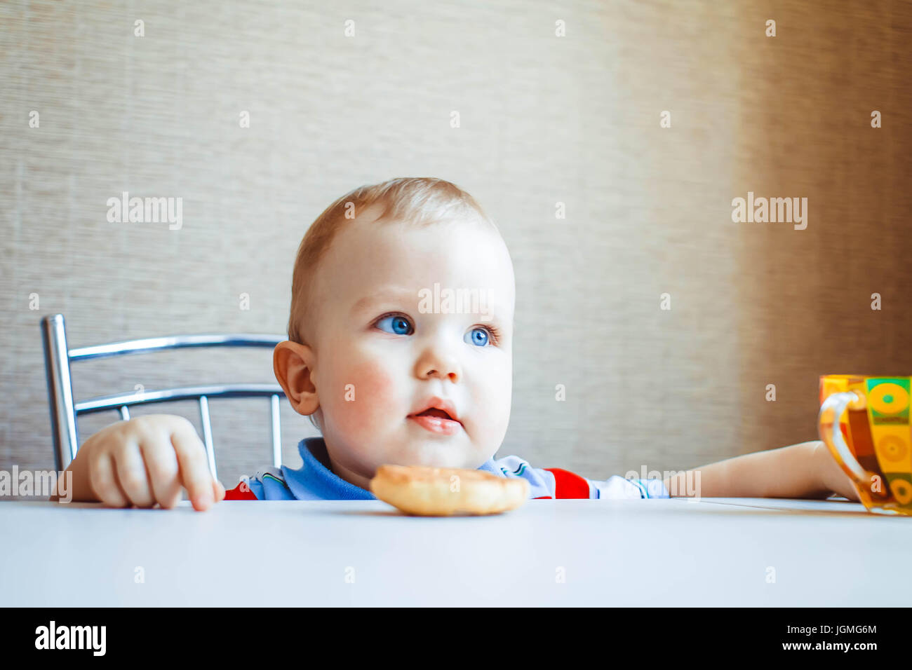 Little boy is sitting at the kitchen table Stock Photo - Alamy