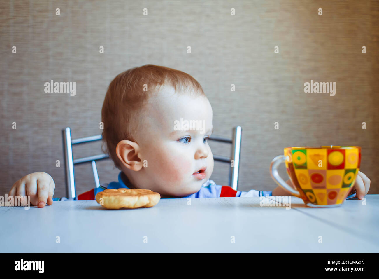 Little boy is sitting at the kitchen table Stock Photo - Alamy