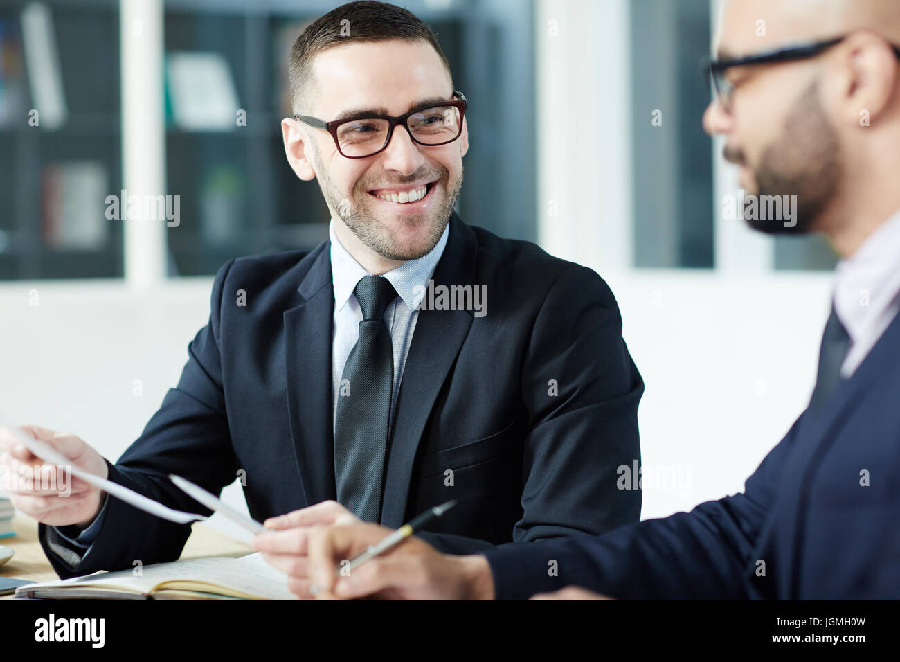 Happy employer looking at business partner during talk Stock Photo - Alamy