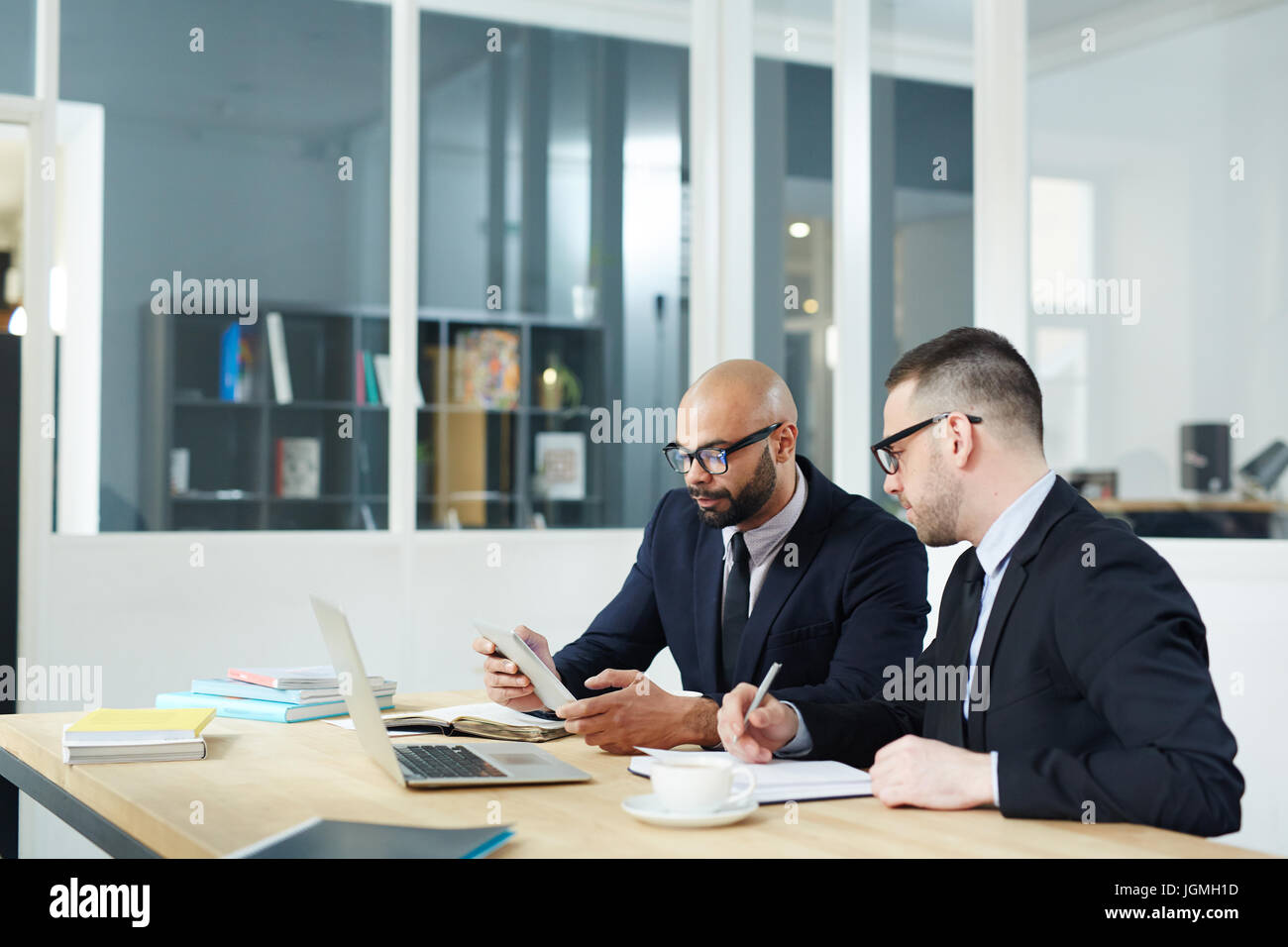 Two office managers with touchpad looking through online data Stock ...