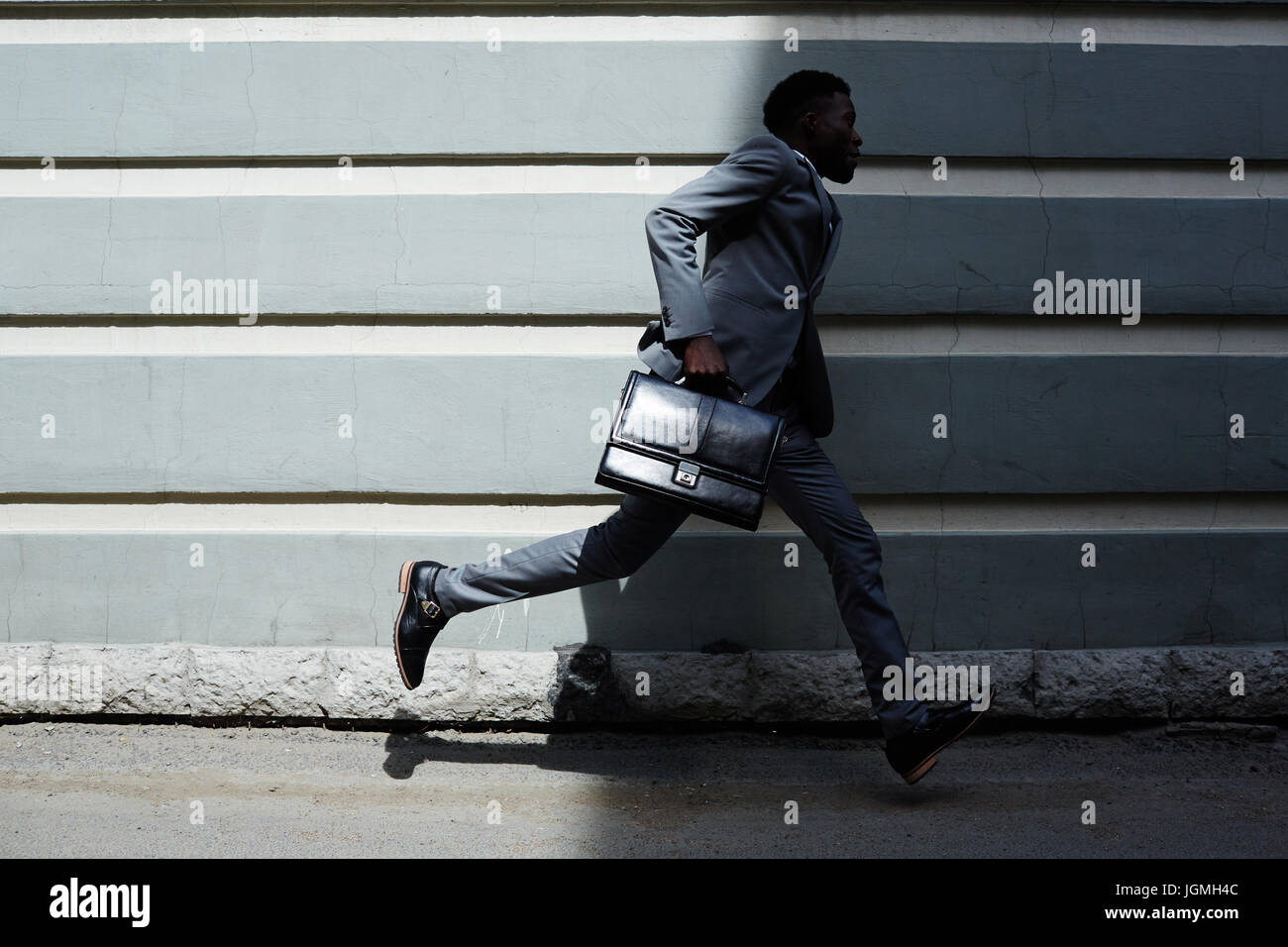 Young businessman running along wall in urban environment Stock Photo ...