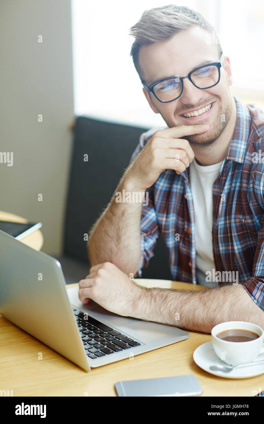 Happy man sitting in cafe in front of laptop Stock Photo - Alamy