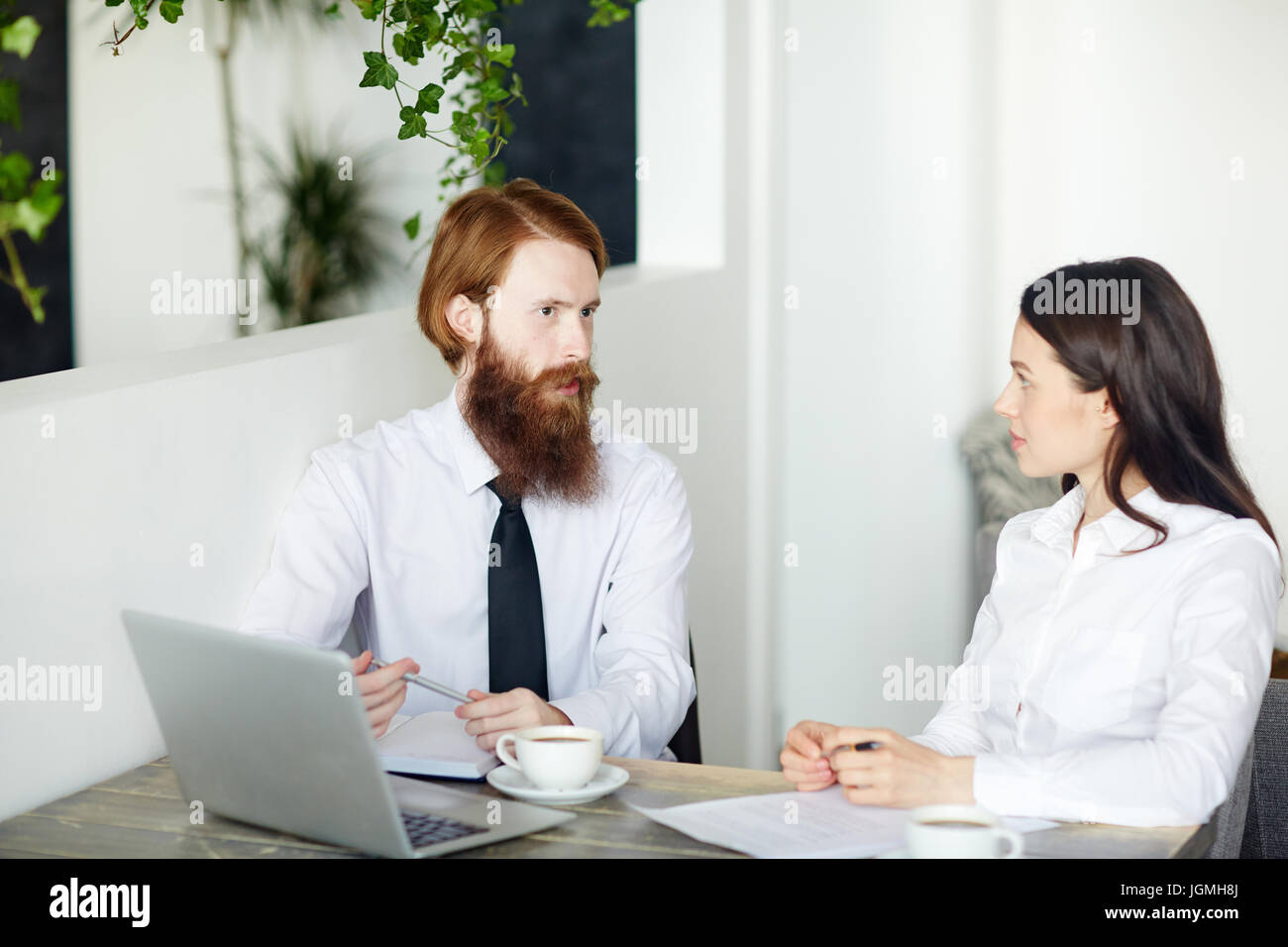 Two young employees having discussion in cafe Stock Photo - Alamy