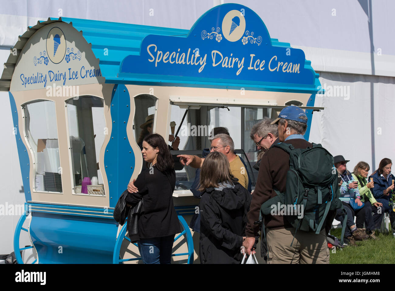 Quaint blue caravan selling ice cream to a queue of waiting people ...