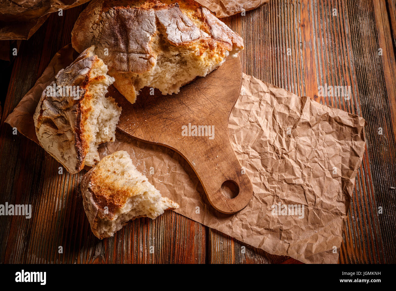 Broken bread in a kraft paper on a wooden rustic background Stock Photo ...