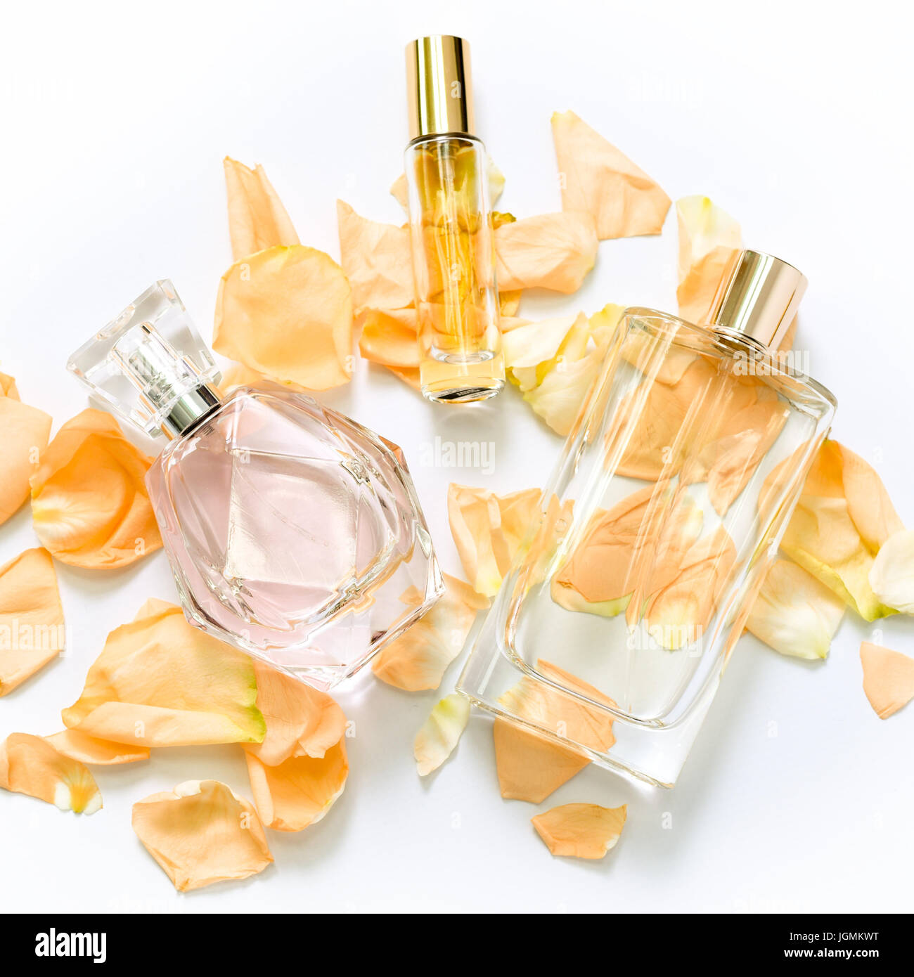 Perfume bottles with flower petals on light background. Perfumery ...