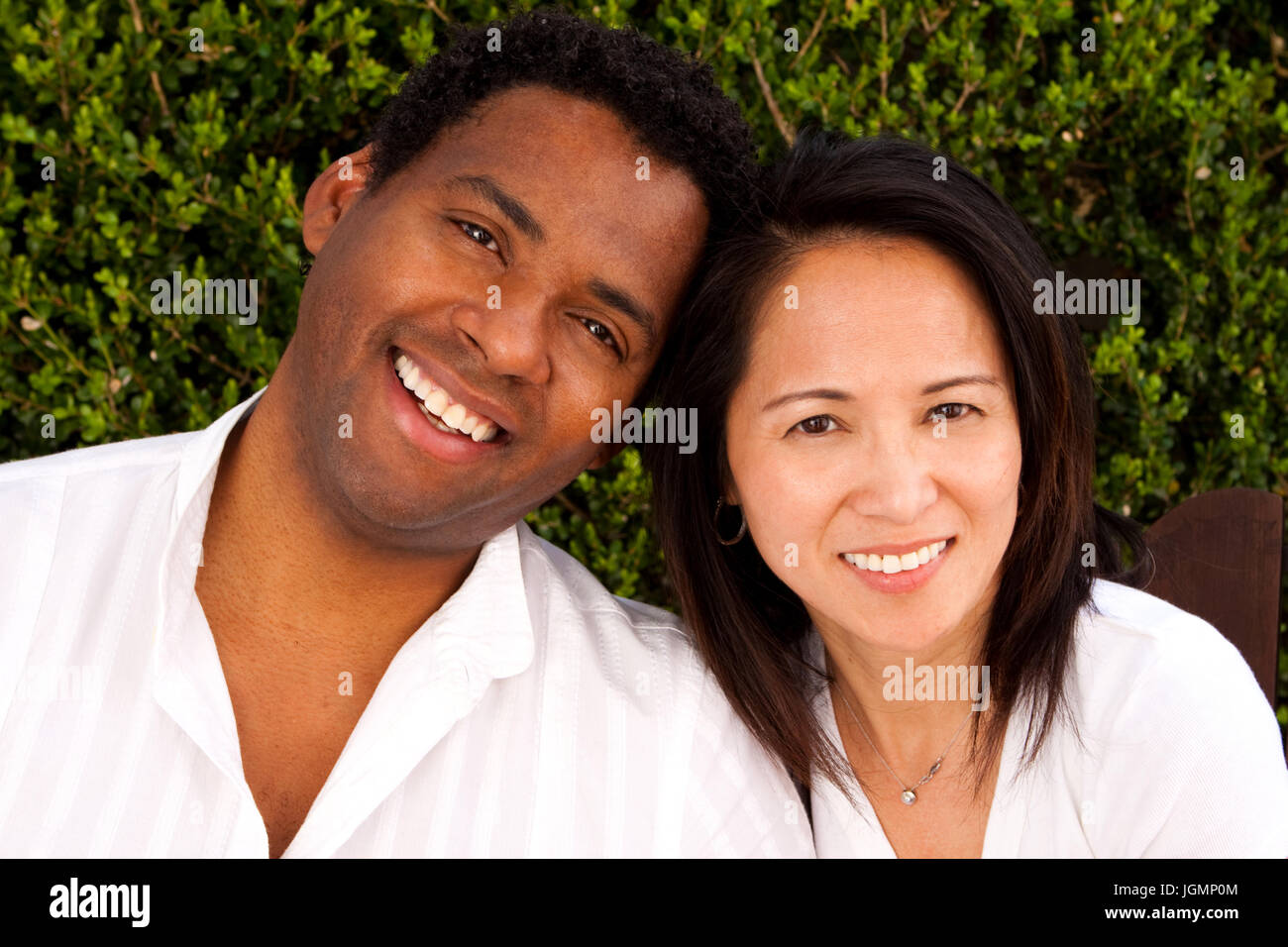 Portrait of a happy biracial couple sitting outside Stock Photo - Alamy